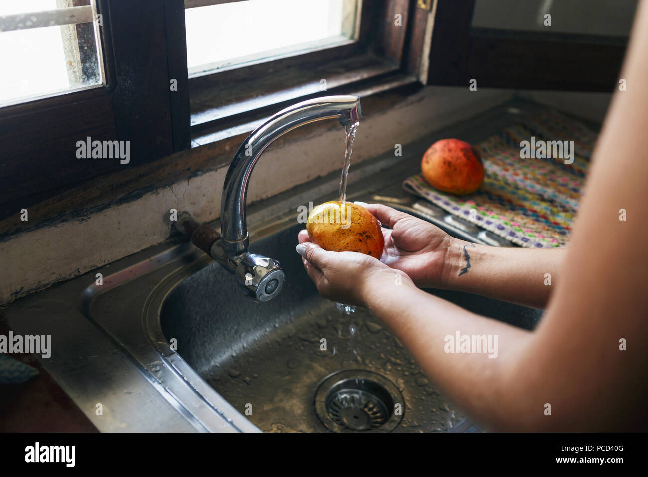 Female hands wash the mango to the home kitchen Stock Photo - Alamy