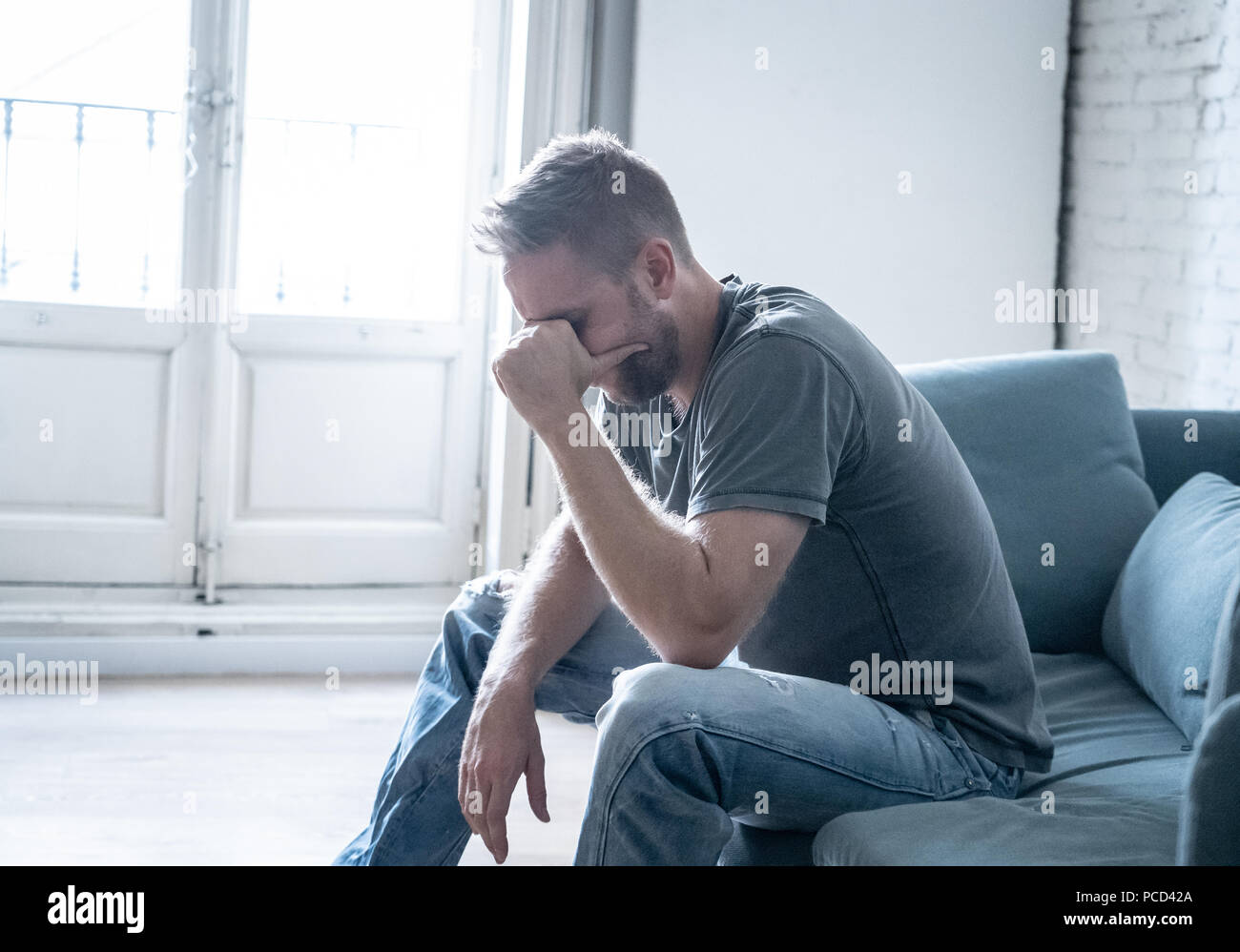 Unhappy depressed caucasian male sitting and lying in living room couch ...