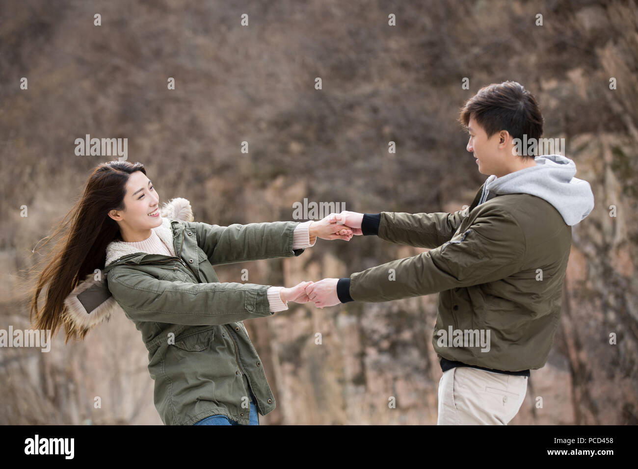 Happy young Chinese couple holding hands spinning Stock Photo - Alamy