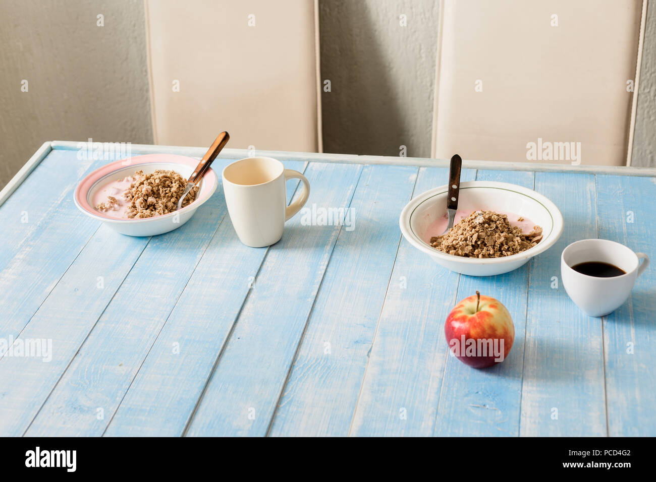 Two plates of cereals with yogurt, apple and cup of coffee on blue ...