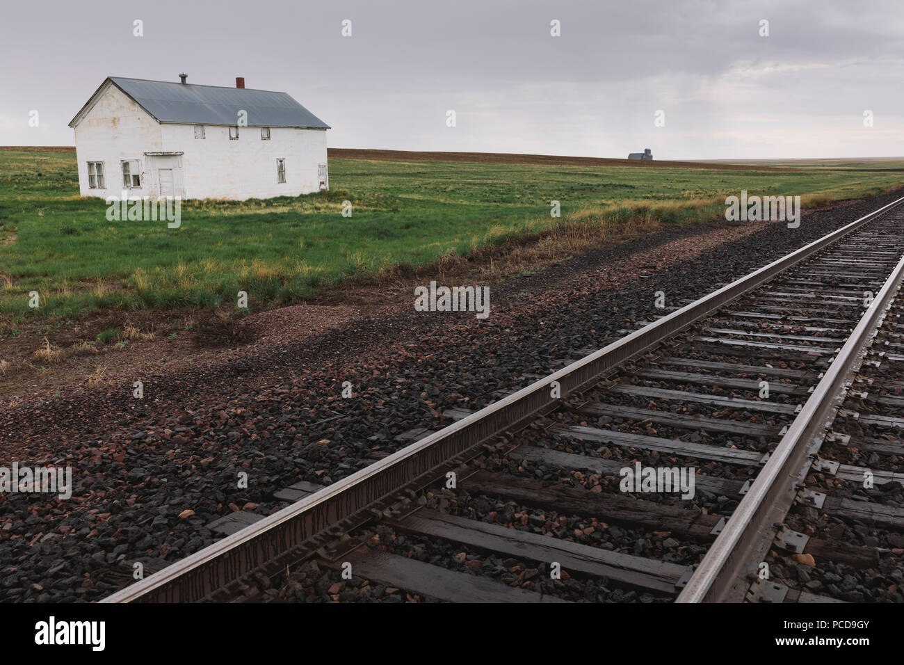 Abandoned farmhouse on prairie, train tracks in foreground ...
