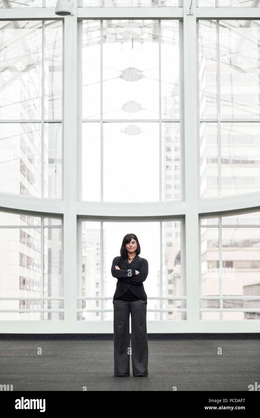 A portrait of a young businesswoman standing in front of a window in a ...