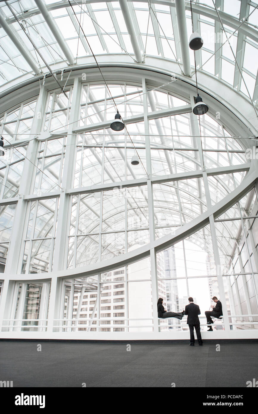 Three businesspeople meeting in front of a window in a large convention ...
