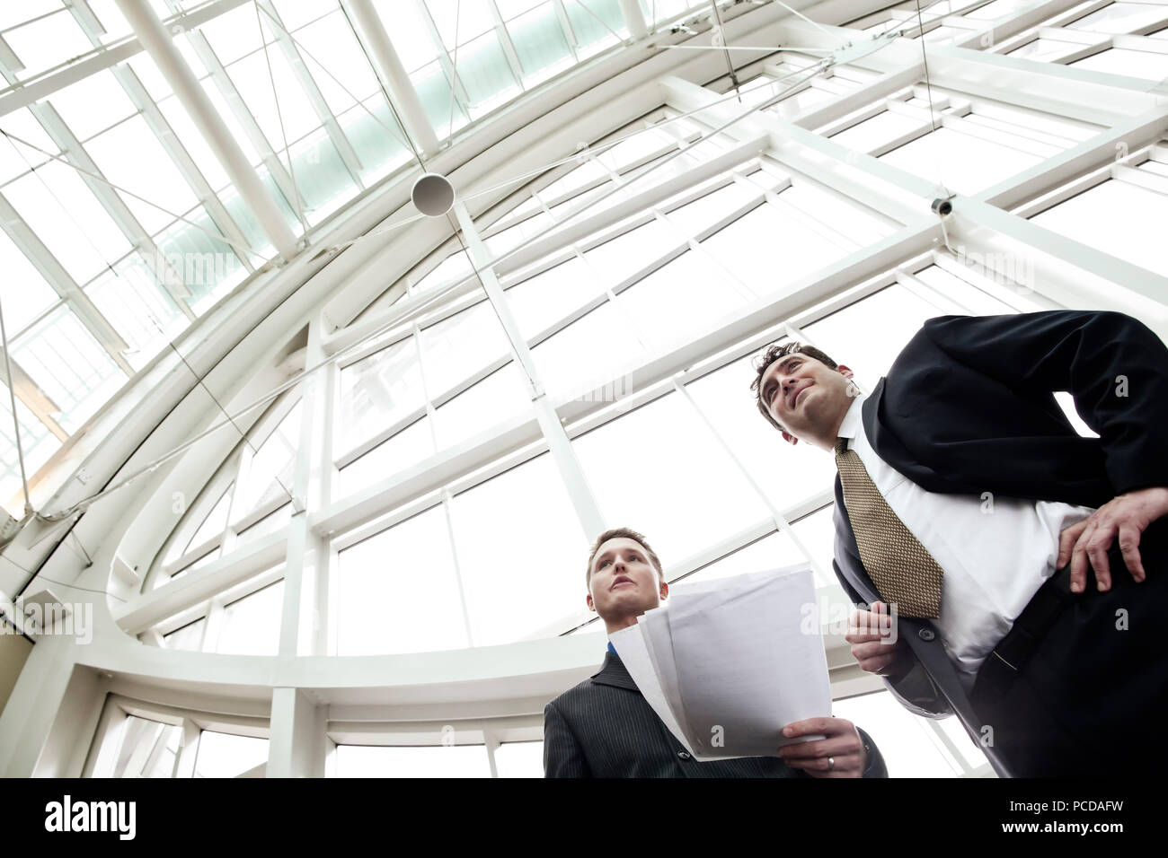 Two businessmen going over paperwork in the lobby of a large convention ...