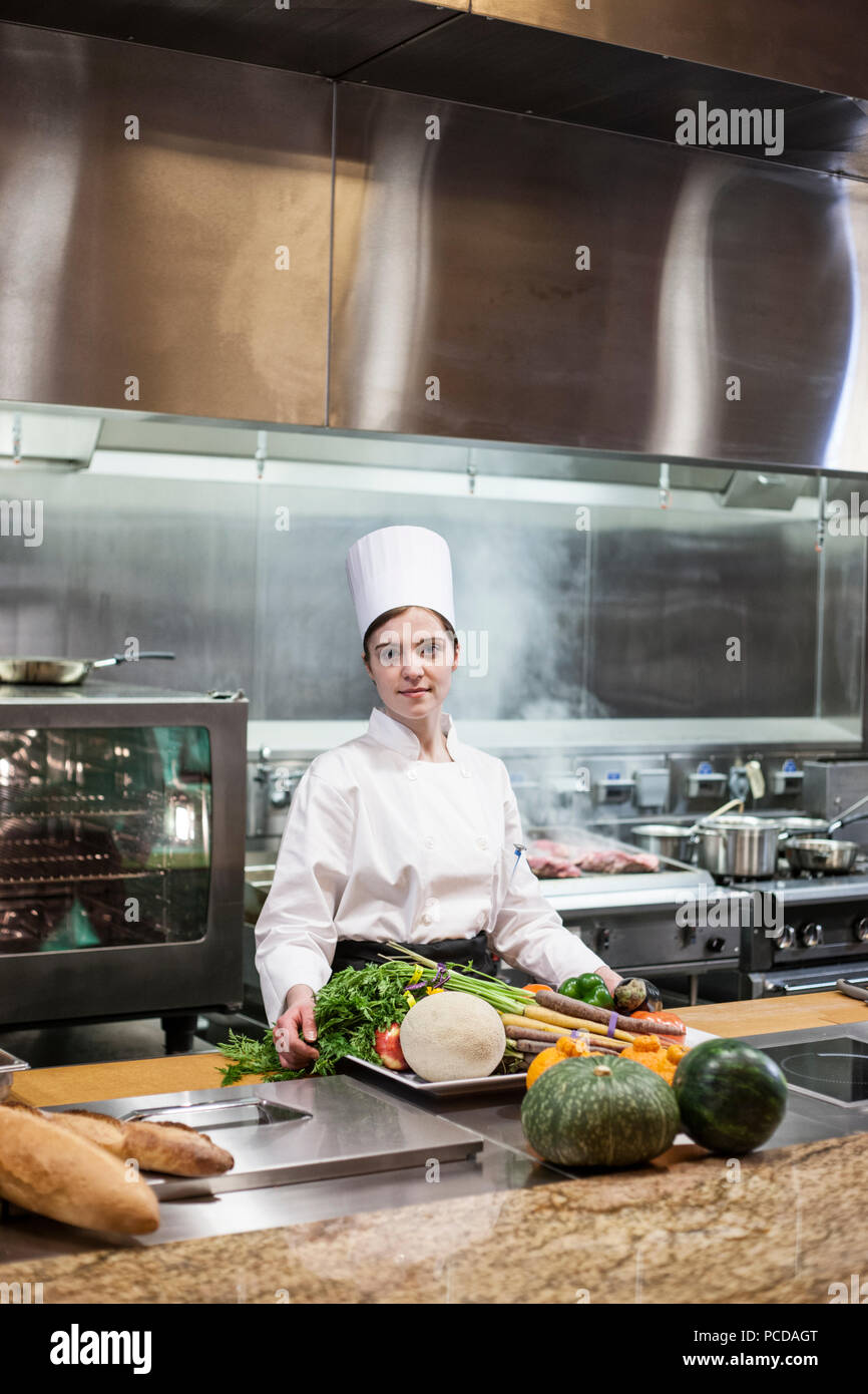 A young caucasian chef working with fresh vegetables in a commercial ...