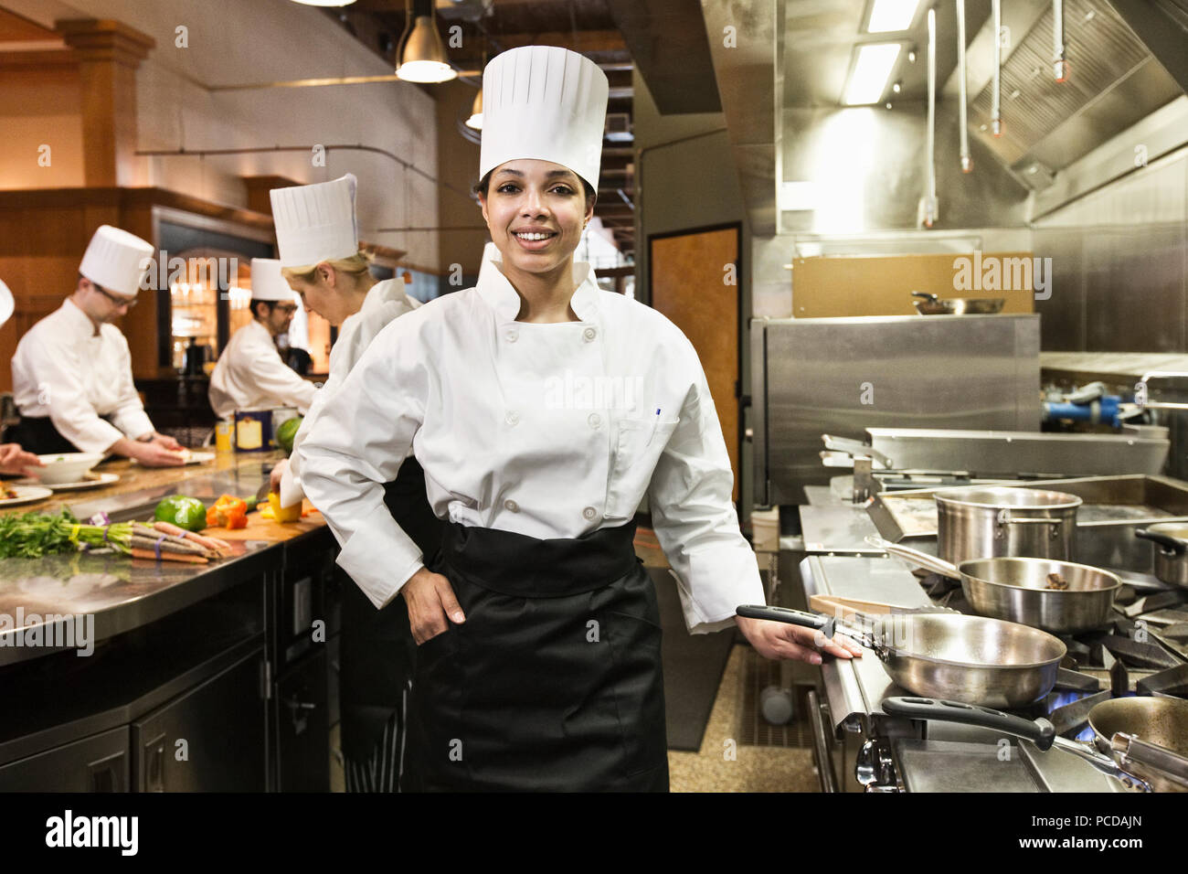 A portrait of a young black female chef in a commercial kitchen with ...