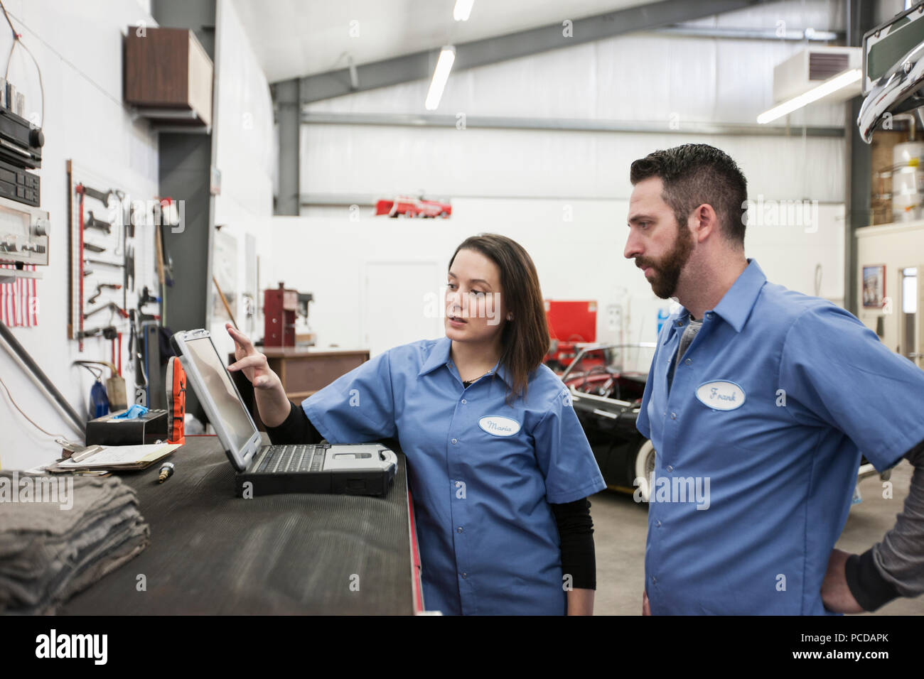 Two mechanics working on a laptop computer in a repair shop Stock Photo ...