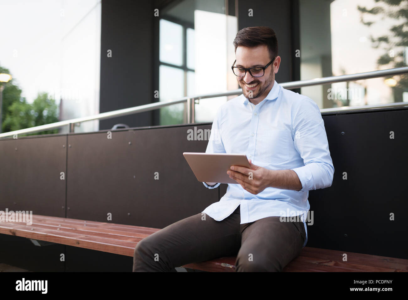 Happy and confident businessman using tablet Stock Photo - Alamy