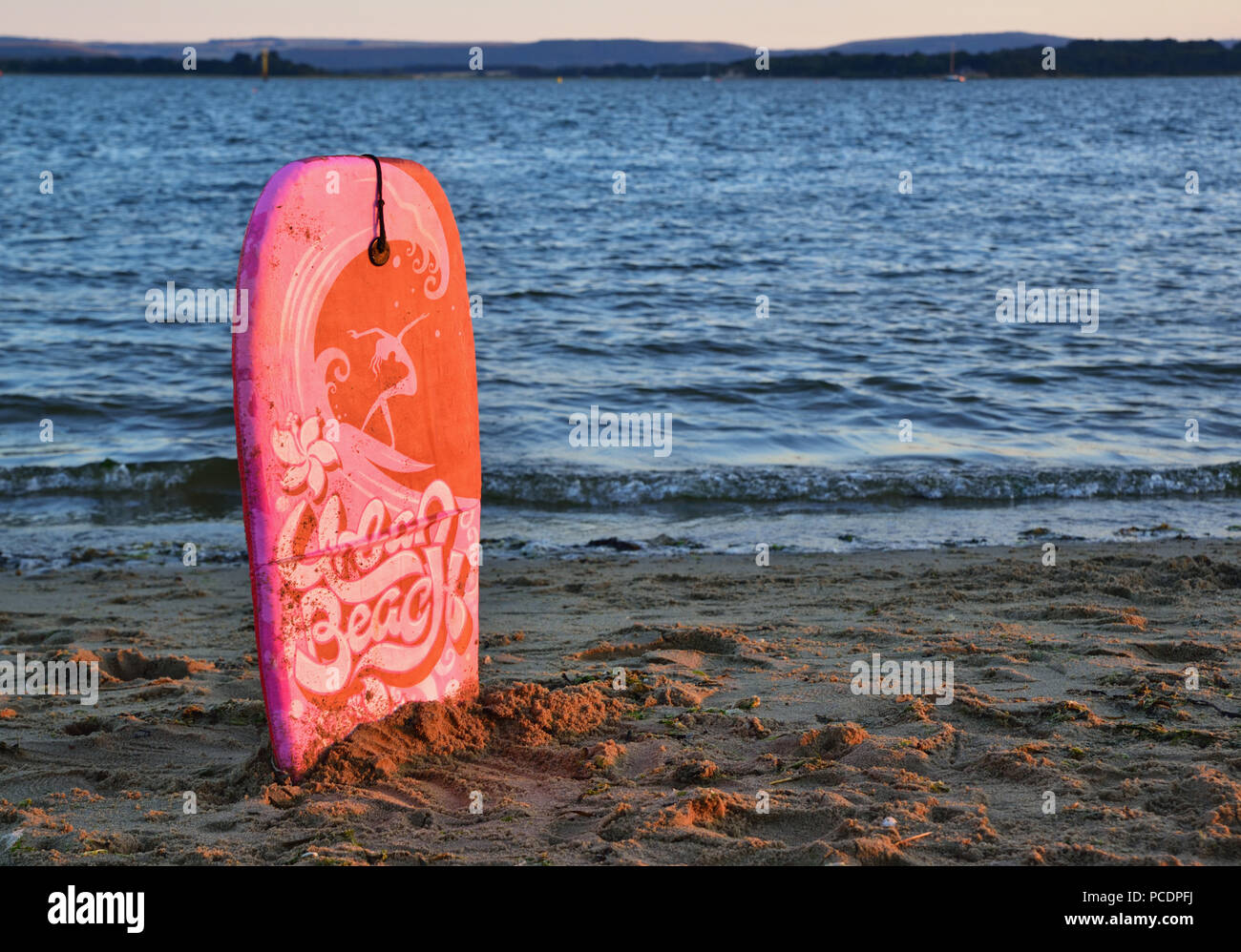 Abandoned child's body board stood on end on the beach Stock Photo - Alamy