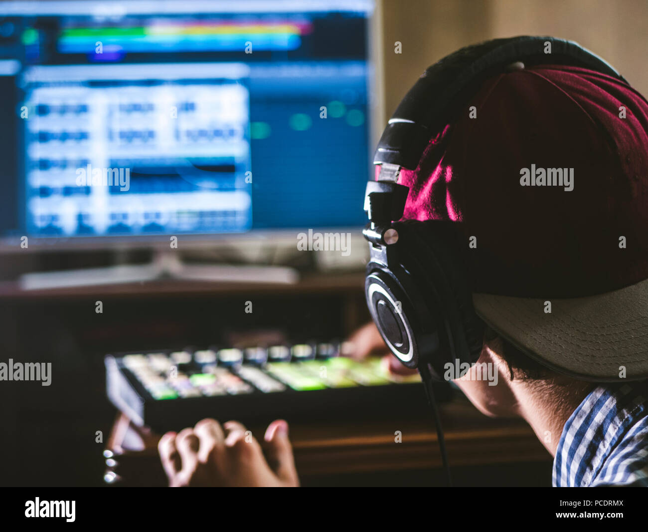 back view of sound engineer in snapback and holding headphones on head ...