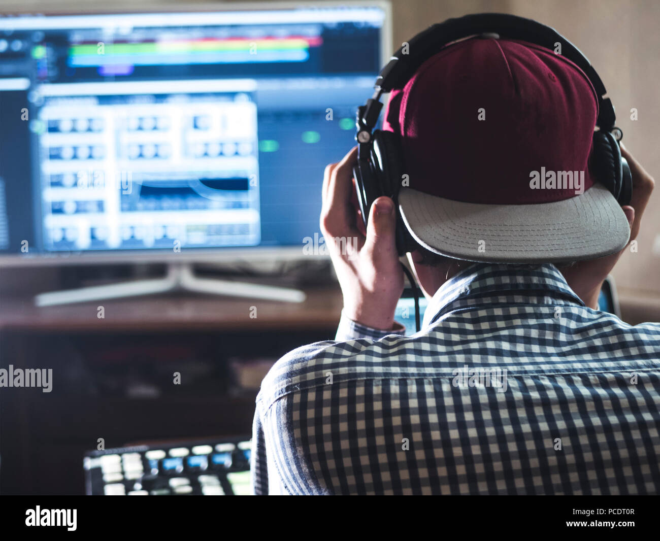 back view of sound engineer in snapback and holding headphones on head ...