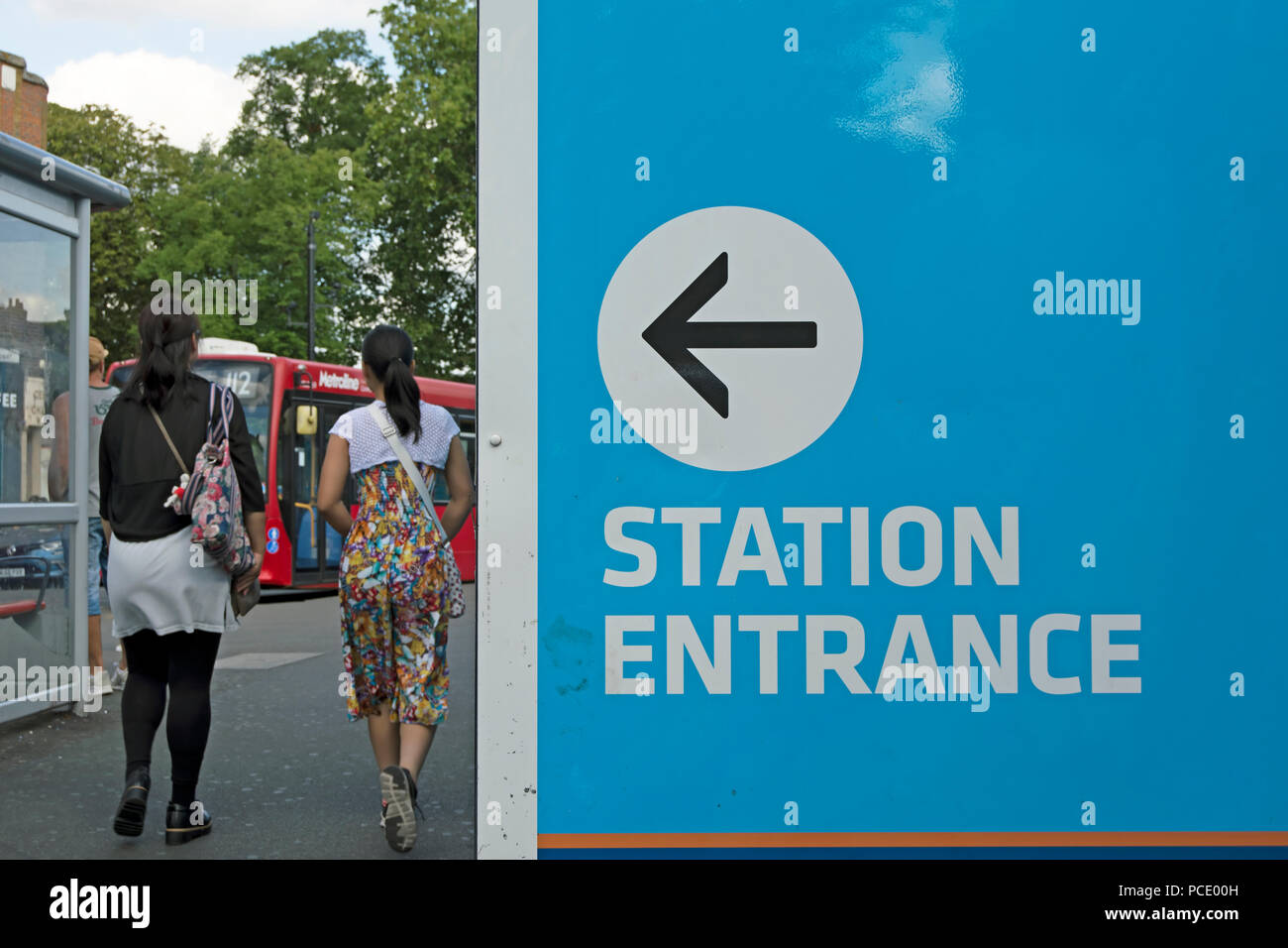two women walk past a sign with arrow indicating the route to the ...