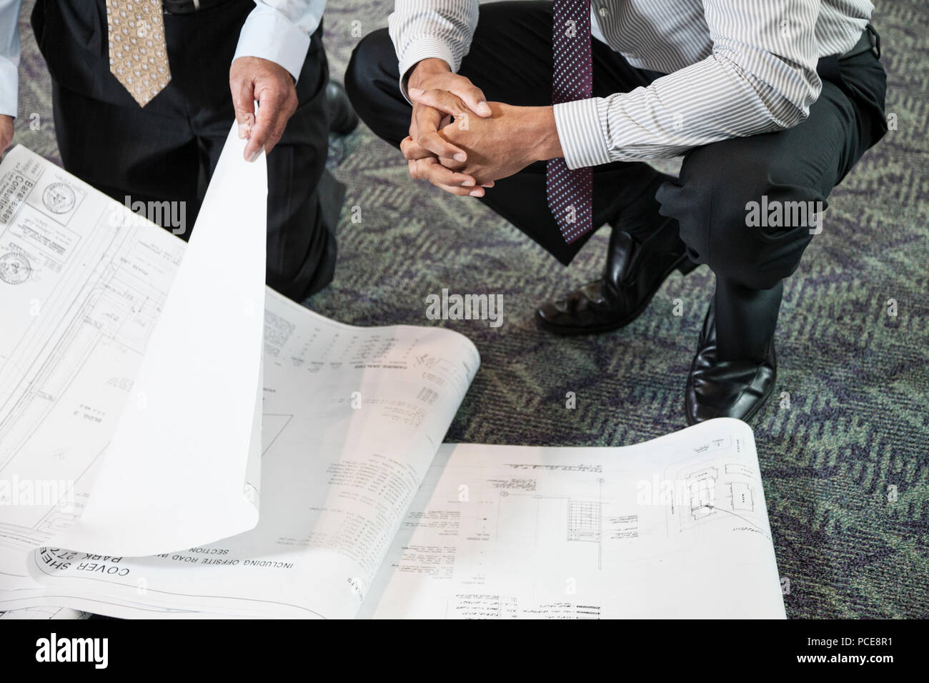 Closeup of two men going over plans for a new office space while ...