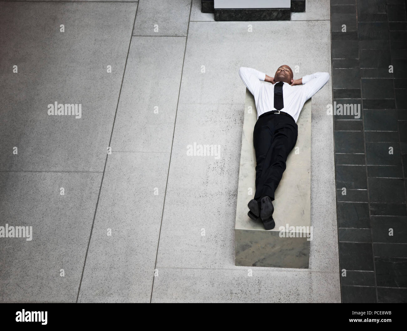 A view looking down on a businessman taking a break laying down on a ...