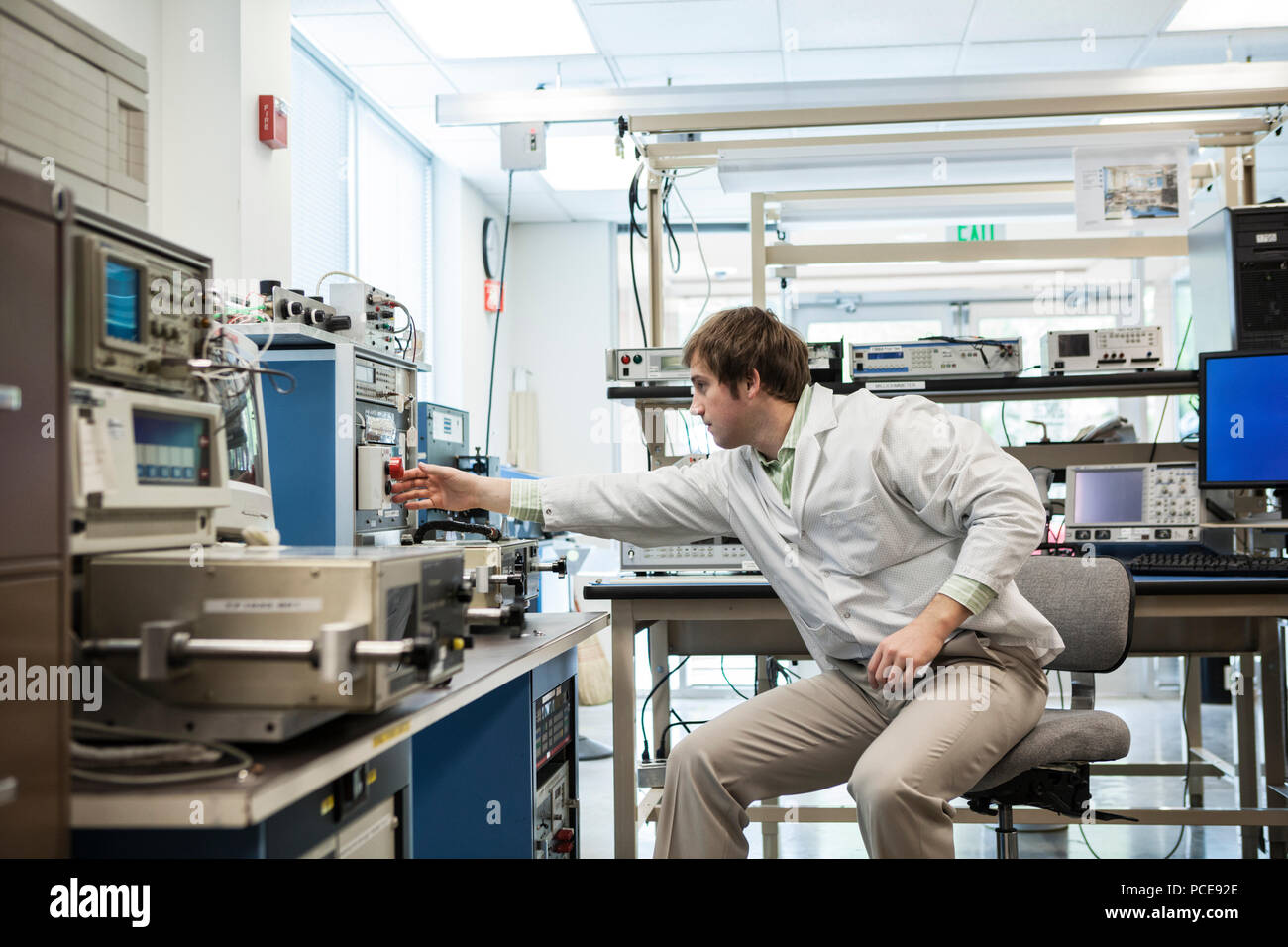 A male caucasian technician sitting at a workbench at a technical ...