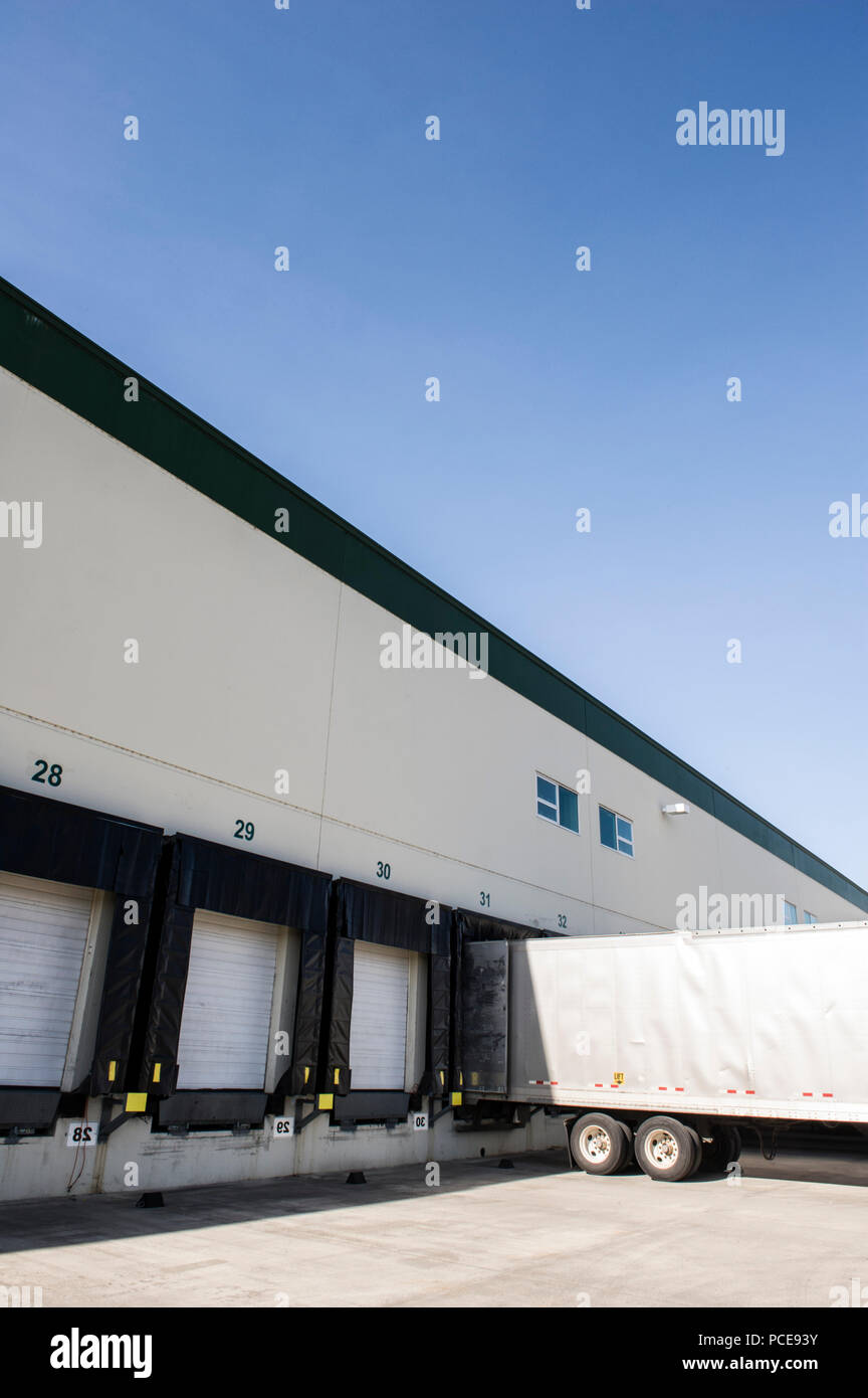 Exterior view of a warehouse loading dock with a truck trailer pulled ...