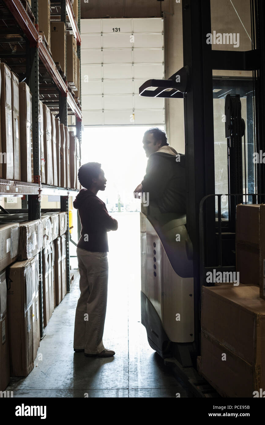 Two warehouse employees talking over an issue while working in a ...