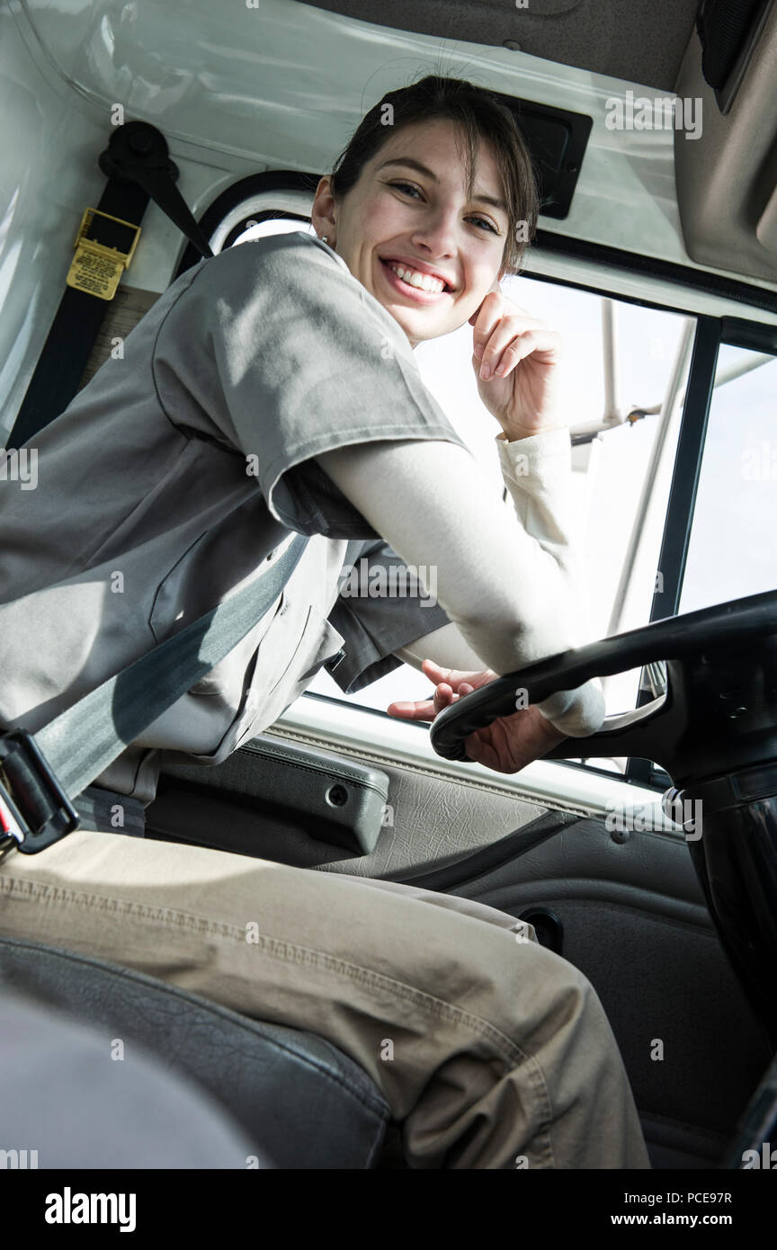 Portrait of a uniformed caucasian female truck driverat the wheel of ...