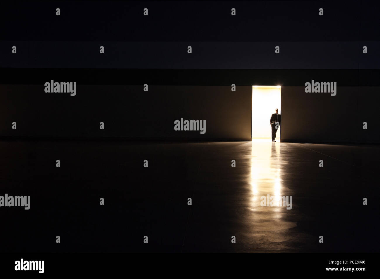 A man in silhouette standing in the doorway of a large convention ...