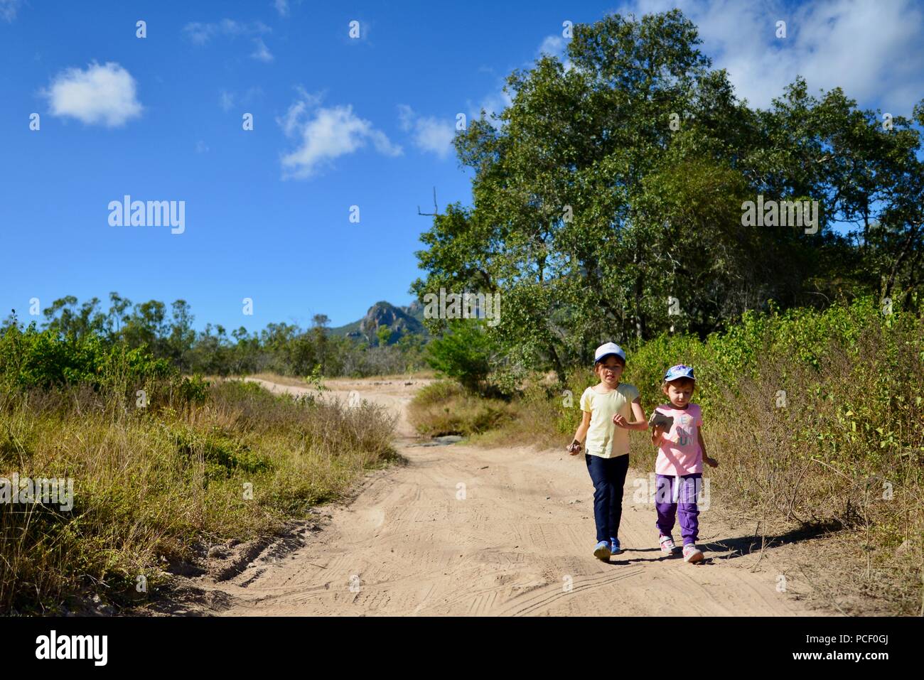 Two children walk down a dry dusty dirt road, Townsville, Queensland ...