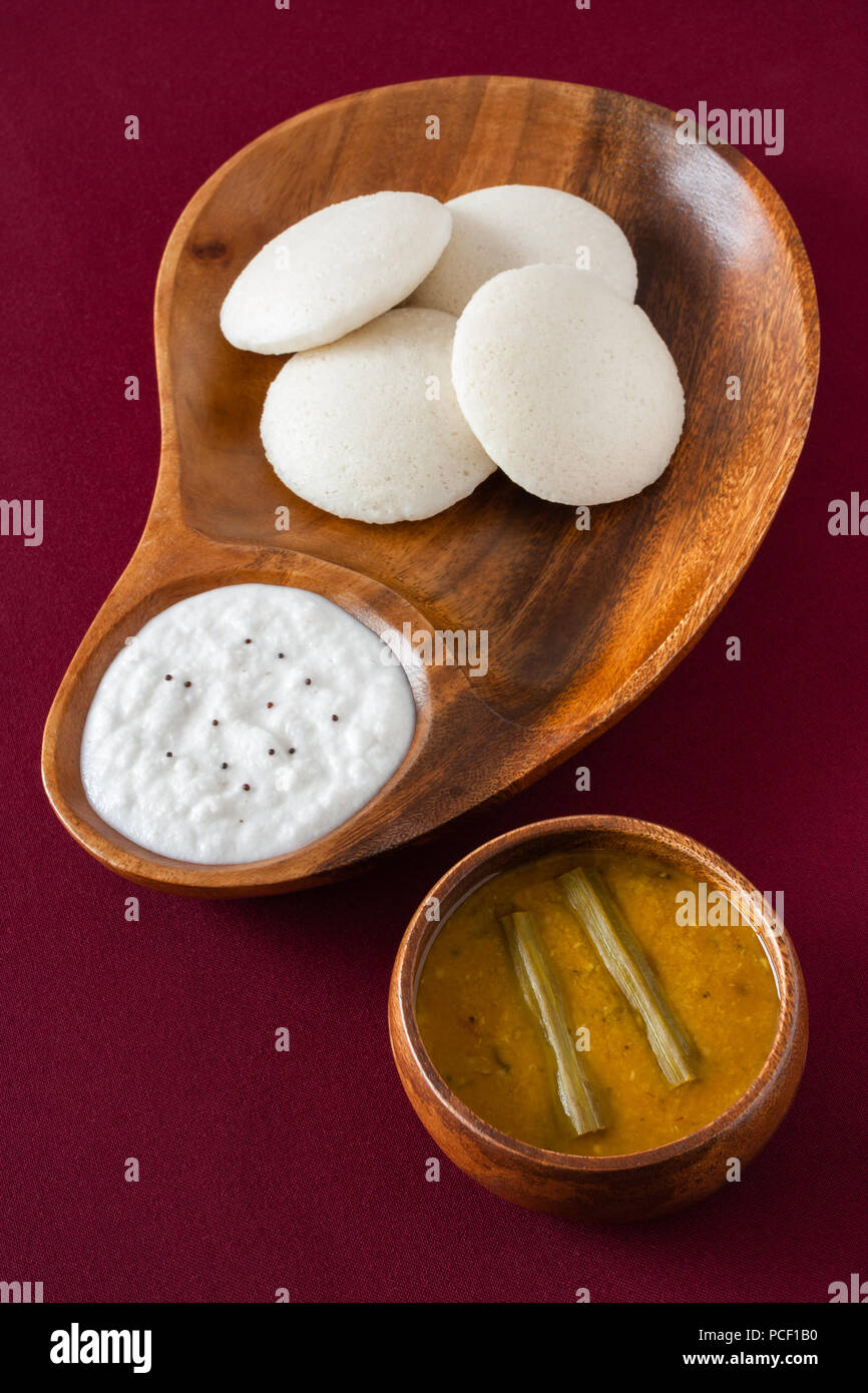Fresh steamed Indian Idly (Idli / rice cake) arranged on a wooden plate ...