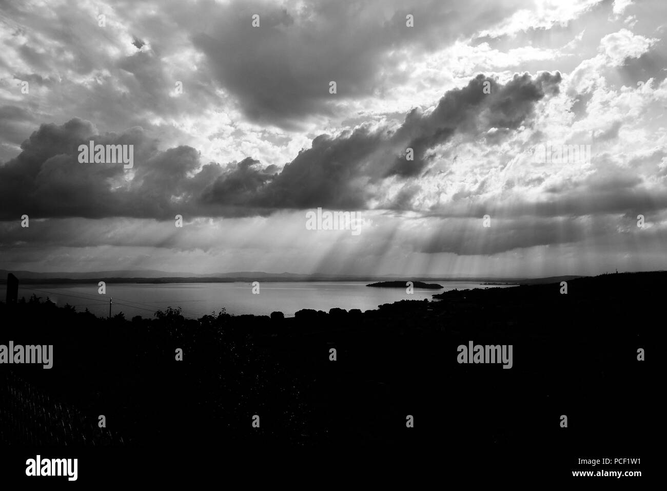 Sun rays coming out through the clouds over an island on a lake Stock ...