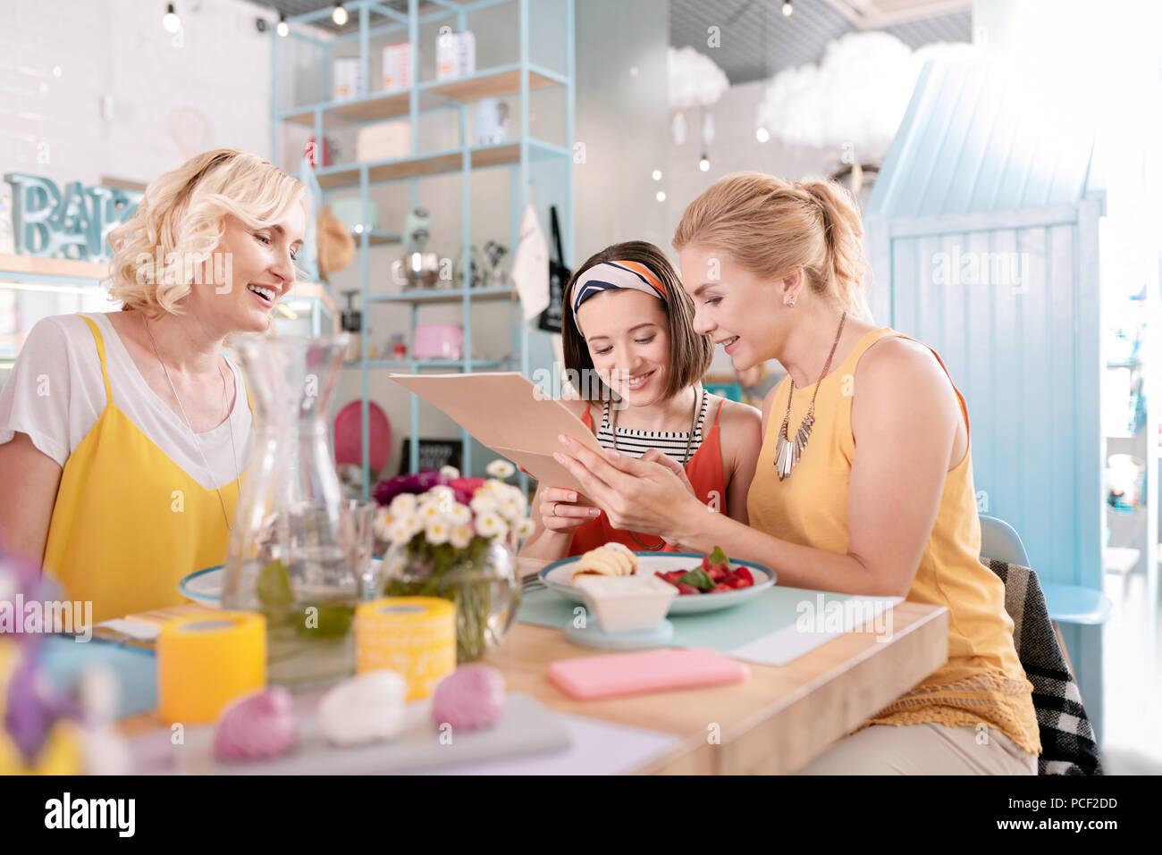 Two friends holding photo album while watching photos Stock Photo - Alamy