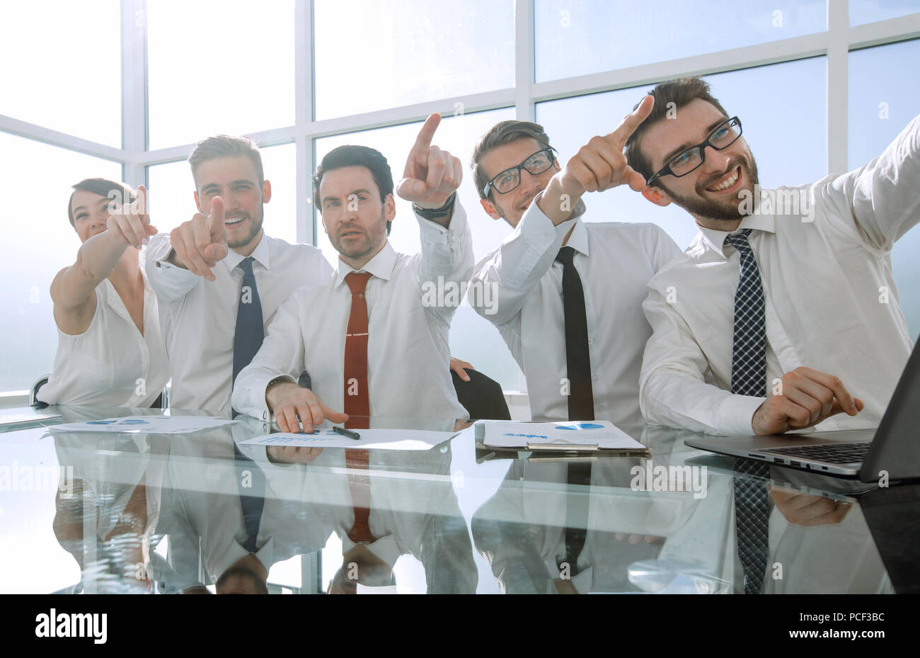 business team sitting at your Desk and pointing at you Stock Photo - Alamy