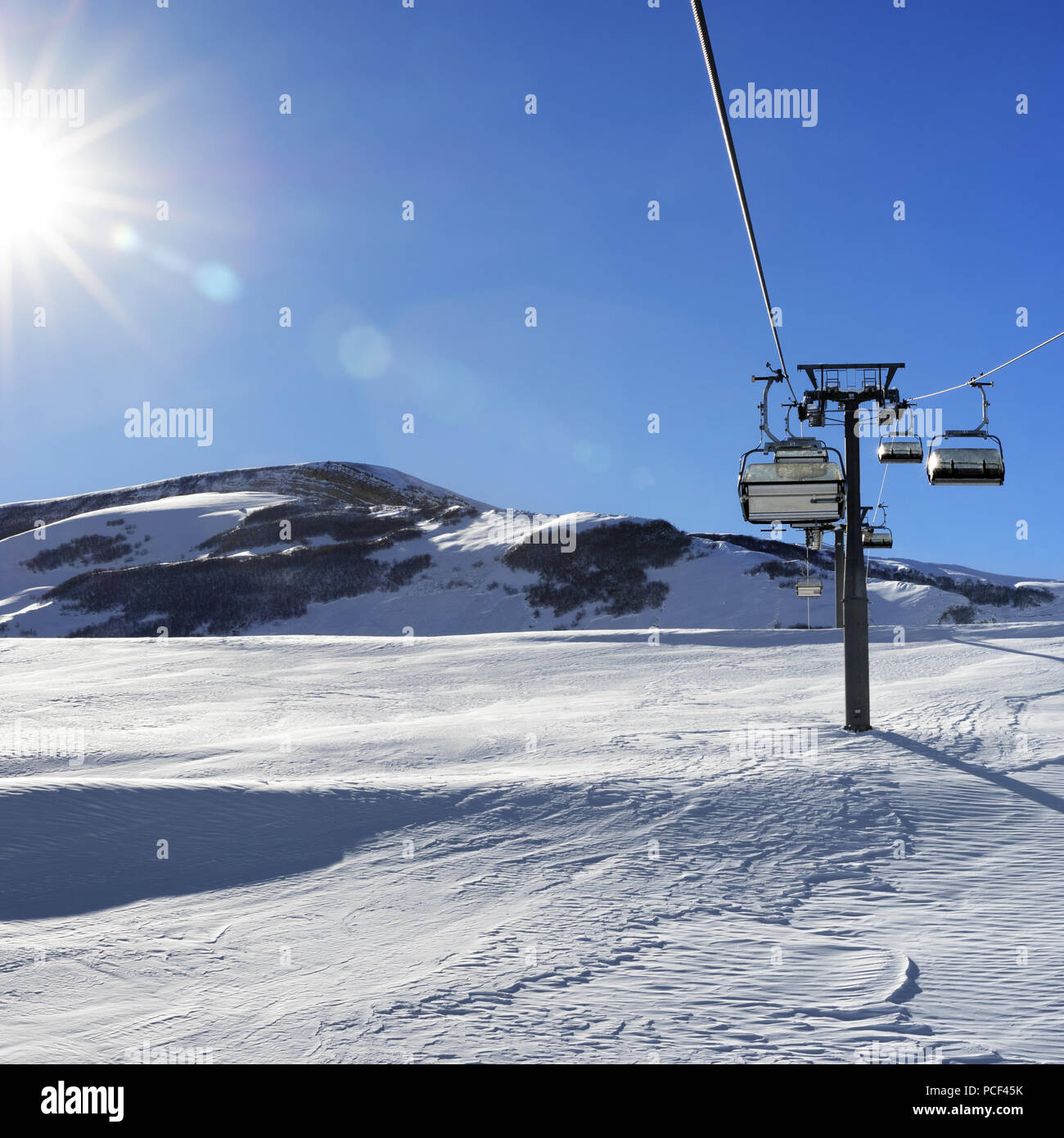 Chair-lift and blue sky with sun and sunbeams. Greater Caucasus in ...