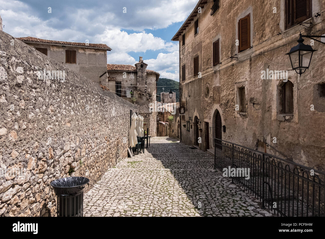 Modern trash bin on a medieval town with mountains on the background ...