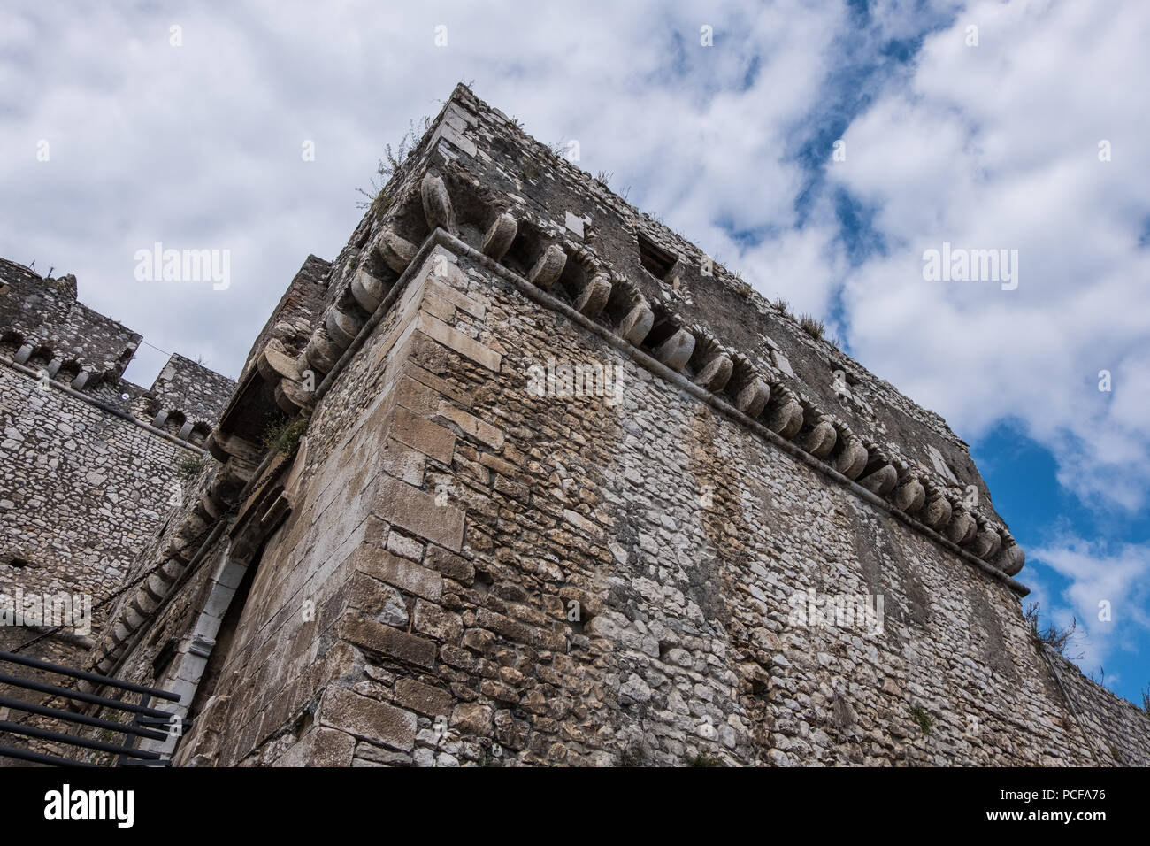 Medieval worn stone castle detail with clouds and blue sky background ...