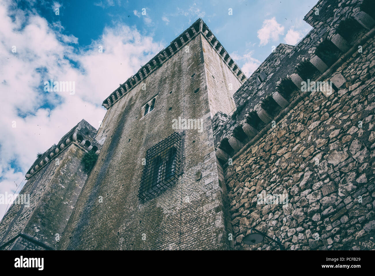 Tower window of a medieval stone castle with blue sky and clouds ...