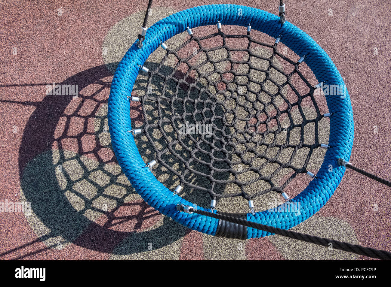 Playground blue net swing with red floor background Stock Photo - Alamy
