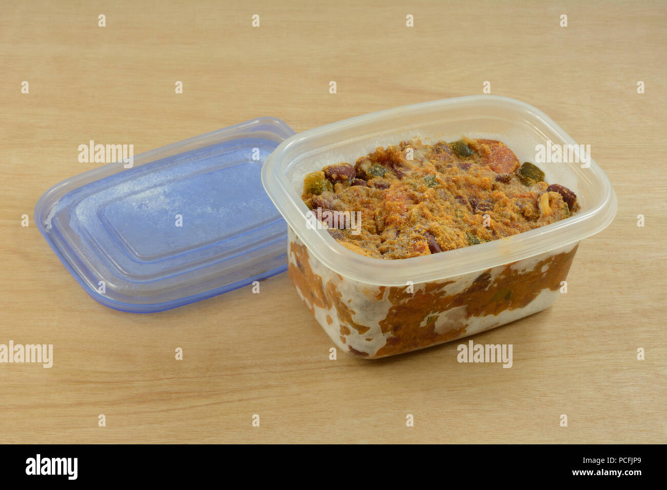Frozen beef chili leftovers thawing in plastic storage container for ...