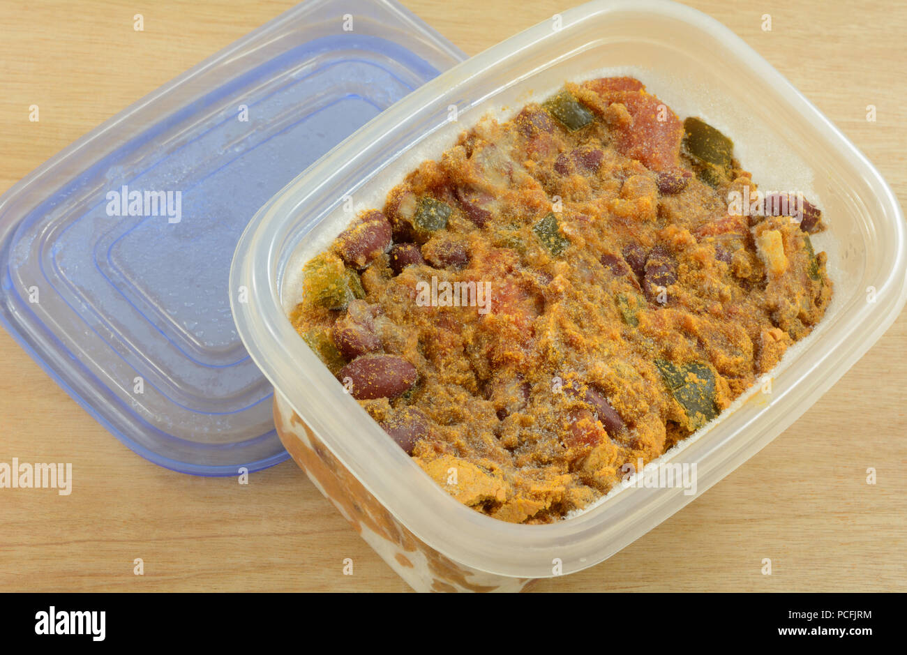 Frozen beef chili leftovers thawing in plastic storage container for ...