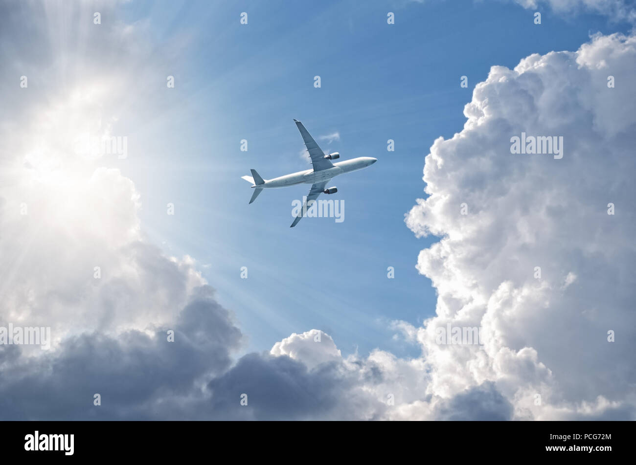 Airplane flying in blue sky, gaining height, sun shine through clouds ...