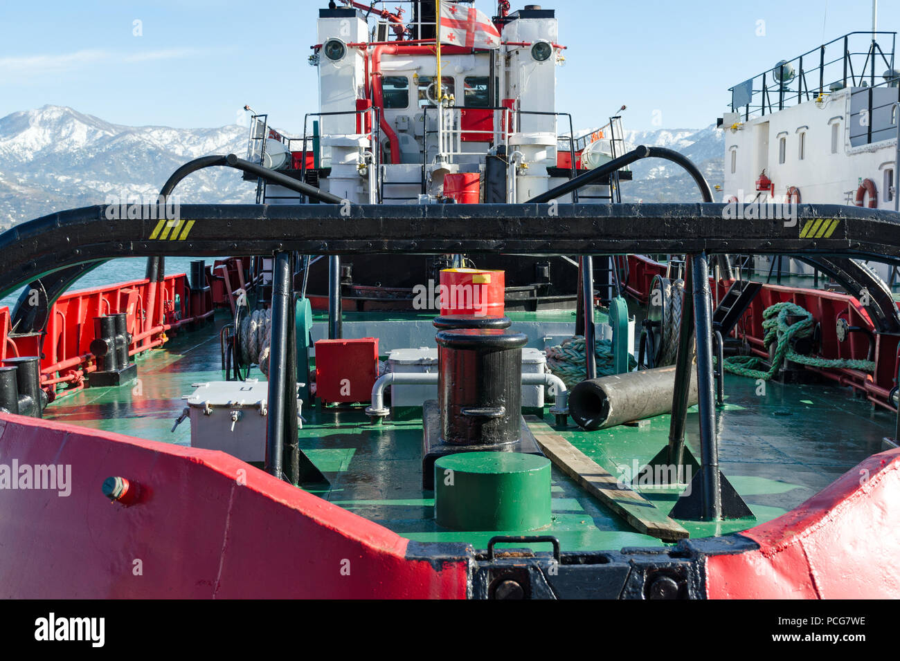 Back view of iron deck tug boat, with flag of Georgia, in background of ...