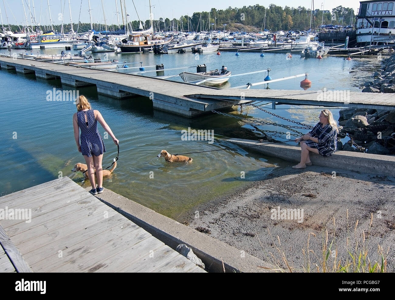 NYNASHAMN, SWEDEN - JULY 18, 2018: Girl and woman walk dogs along the ...