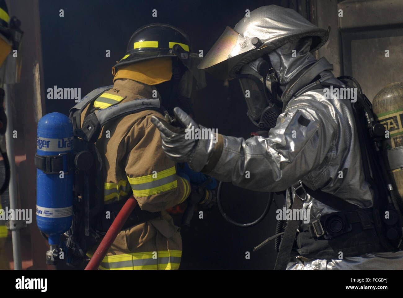 A mentor directs Afghan Air Force airmen into a space containing a fire ...