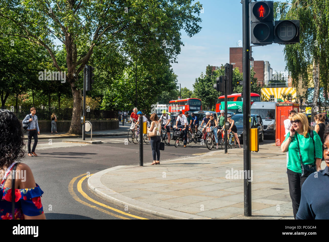 Cyclists waiting at traffic lights in front of taxis, card and red ...