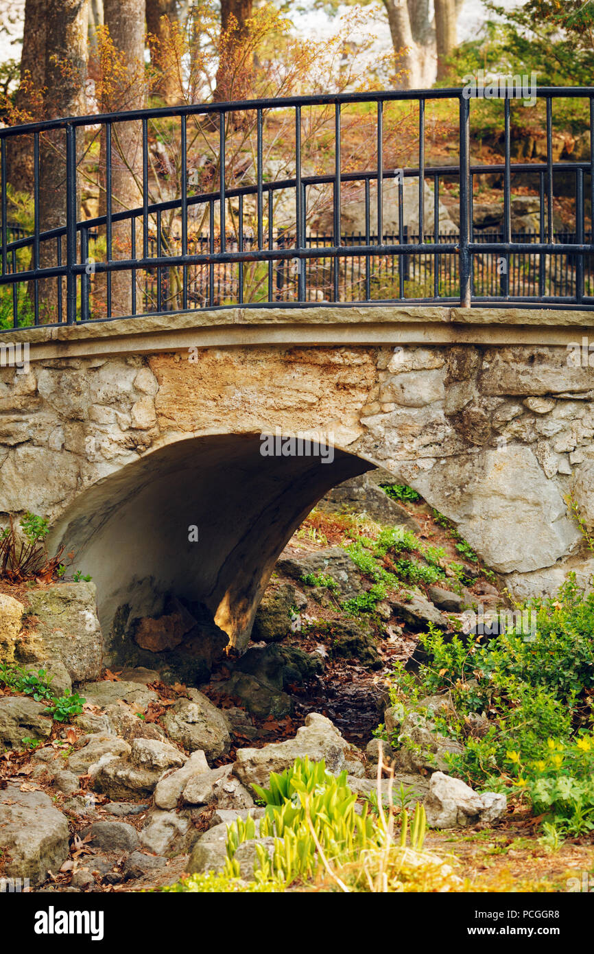 Small cute old stone bridge with archway in park with dried up river ...