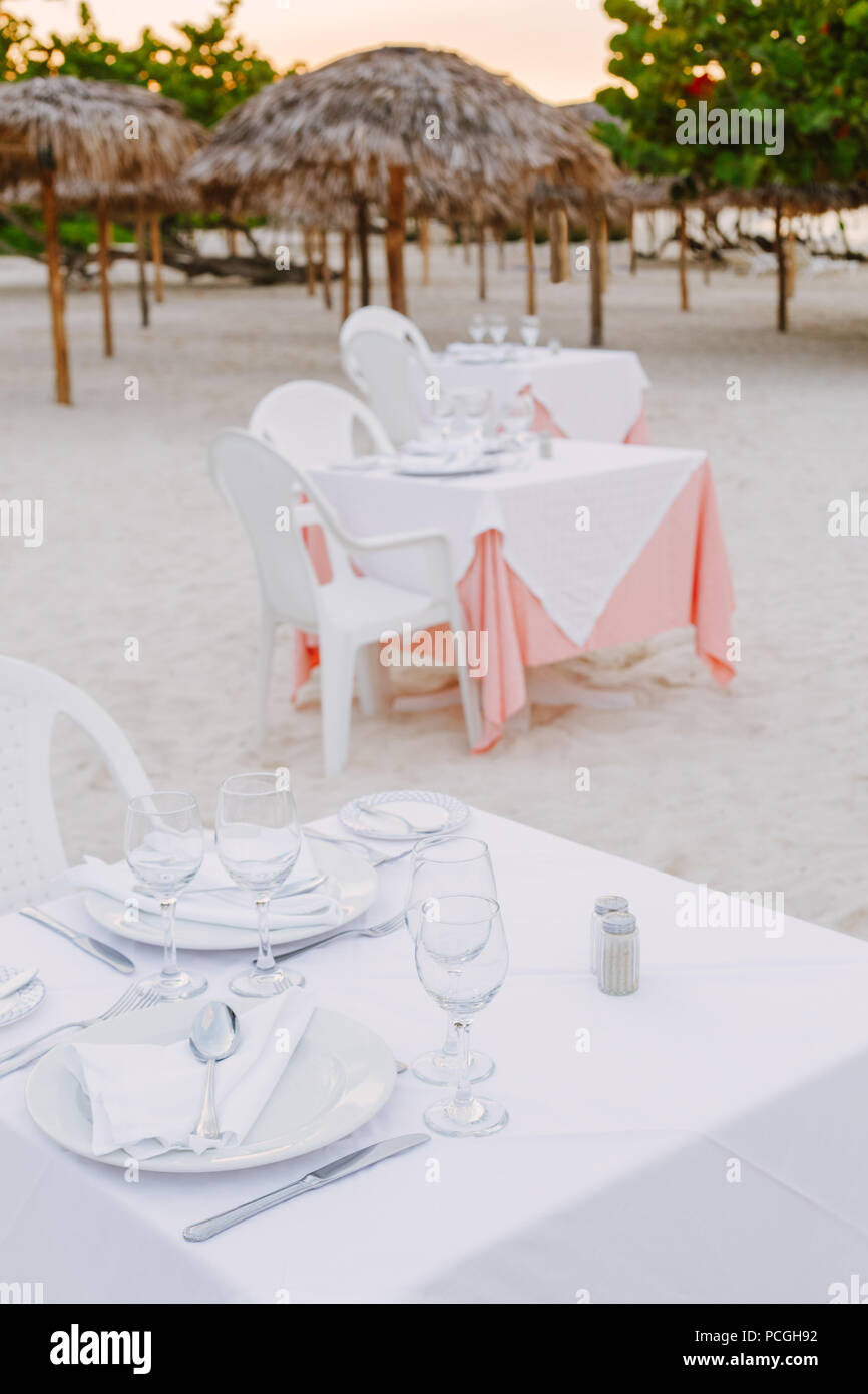 Group row of many tables standing on sea ocean sand beach at sunset ...