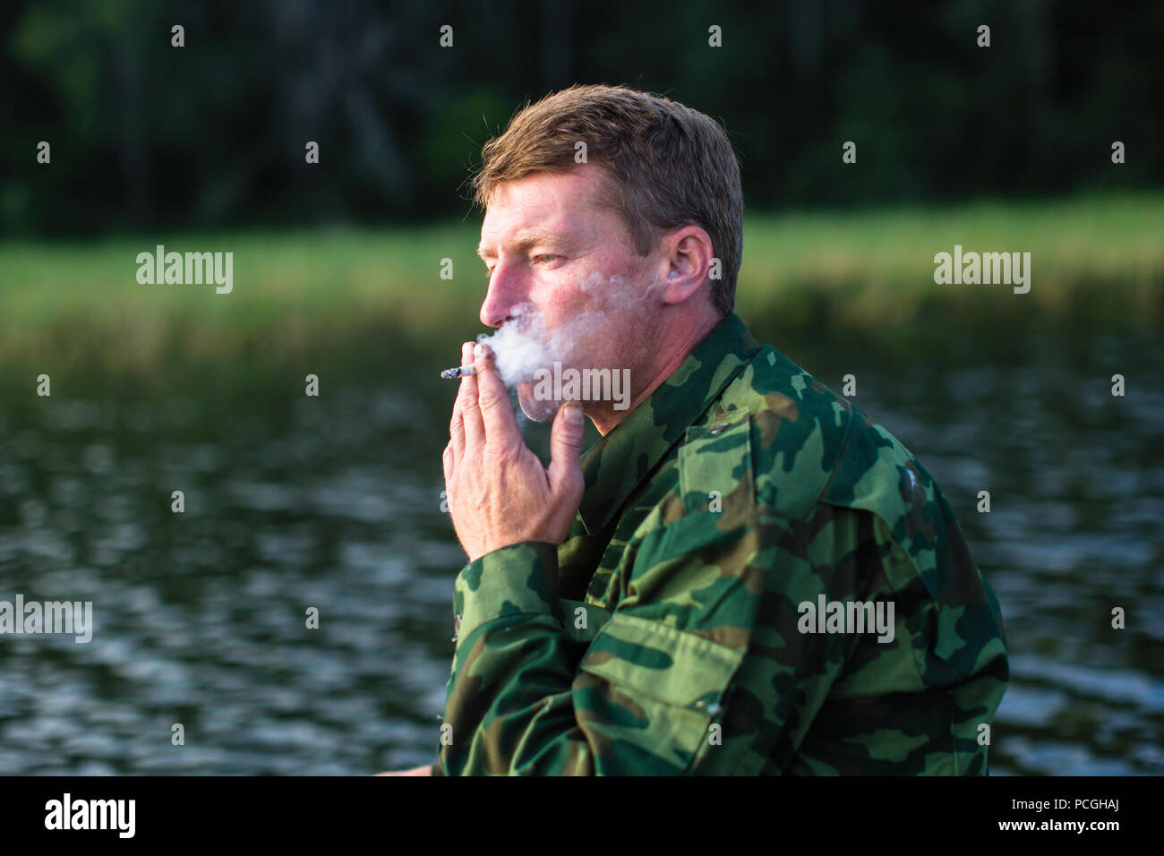 A man in camouflage smoking a cigarette outdoors Stock Photo - Alamy
