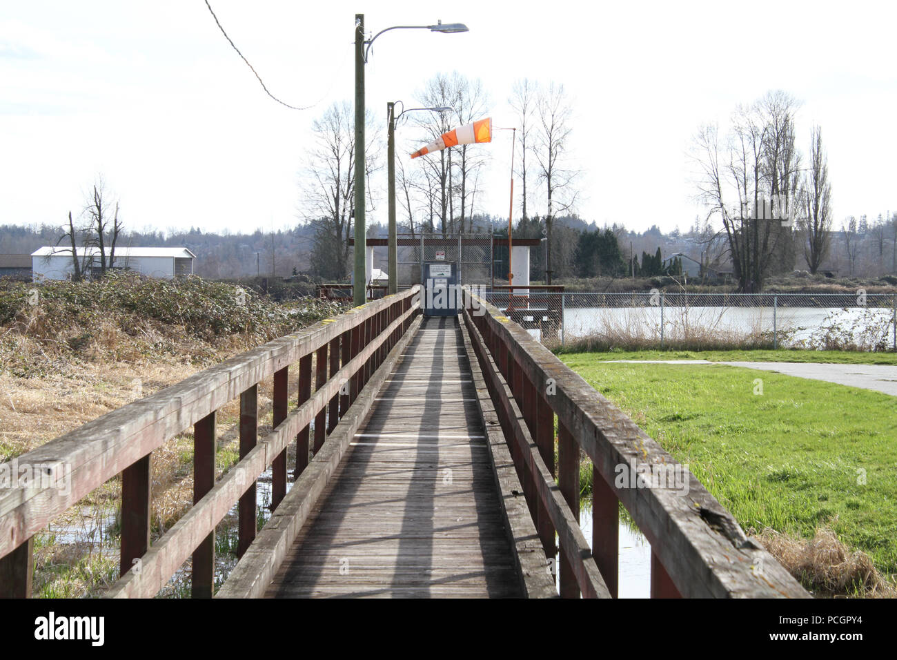A wooden walkway leading to a gate and sign on the edge of the river ...