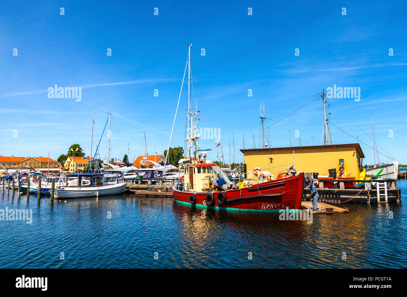 Fisherman working on his boat moored in the harbour at Dragør fishing ...