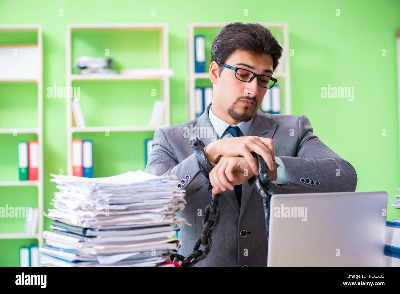 Employee chained to his desk due to workload Stock Photo - Alamy