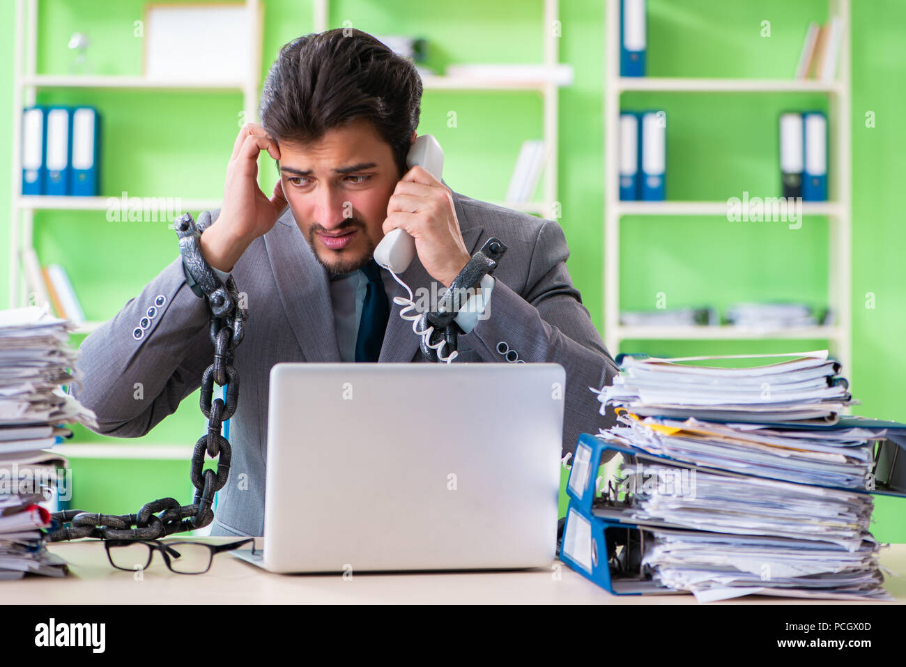 Employee chained to his desk due to workload Stock Photo - Alamy