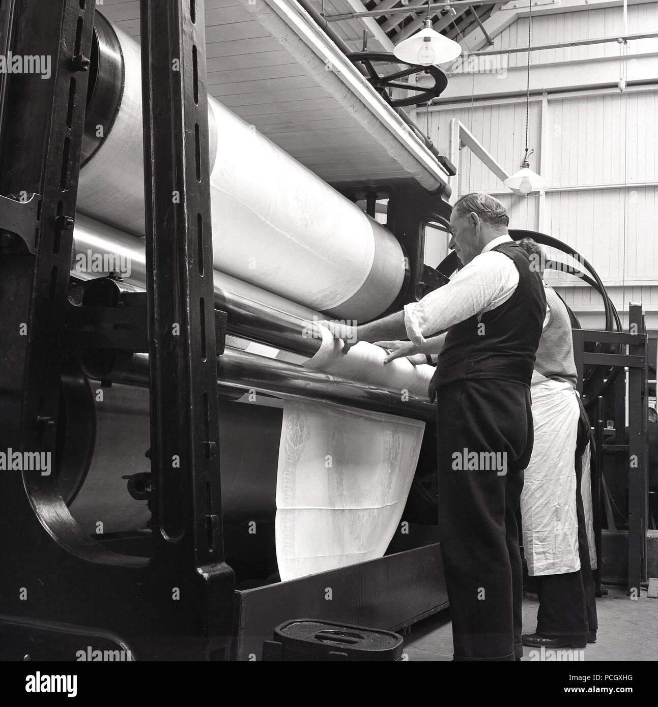 1950s, historical, two male workers standing by large rollers with ...