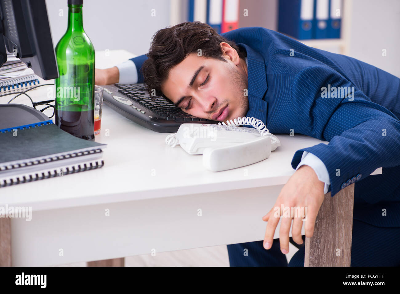 Young businessman employee drinking in the office at desk Stock Photo ...