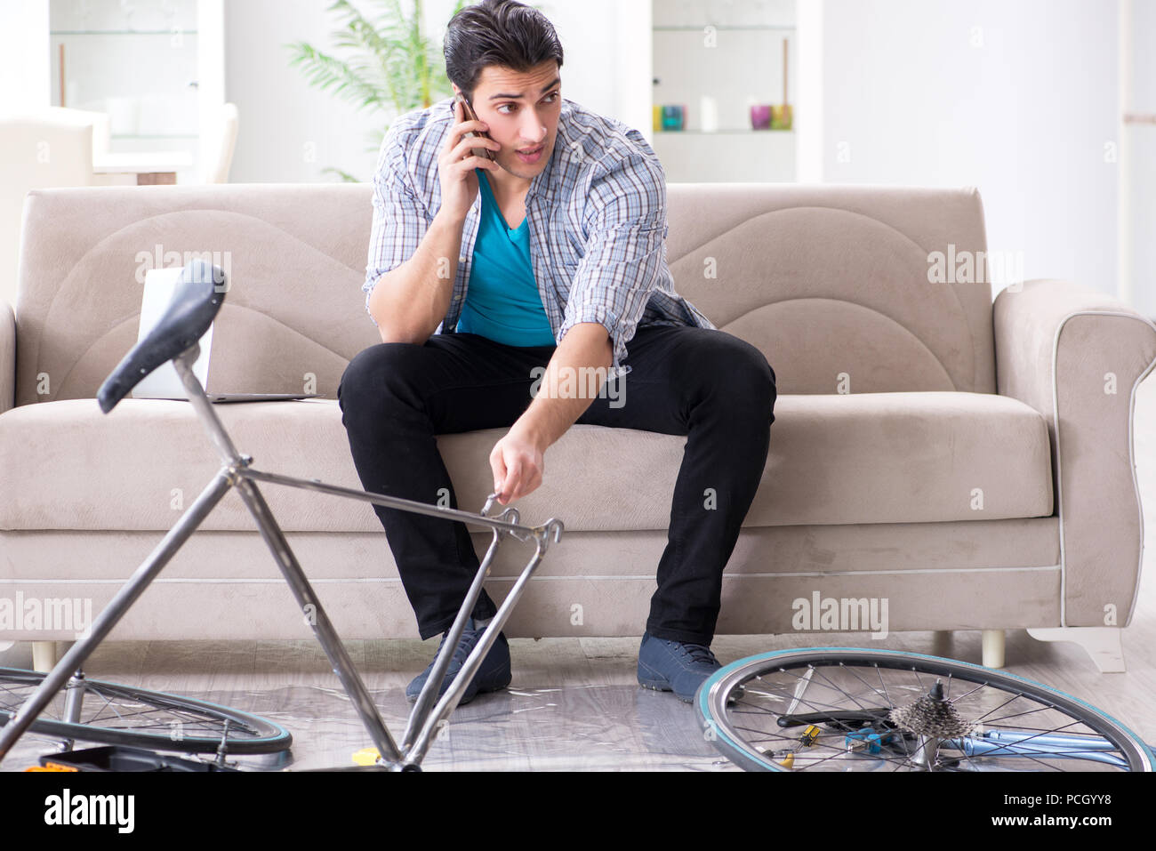 Young man repairing bicycle at home Stock Photo - Alamy